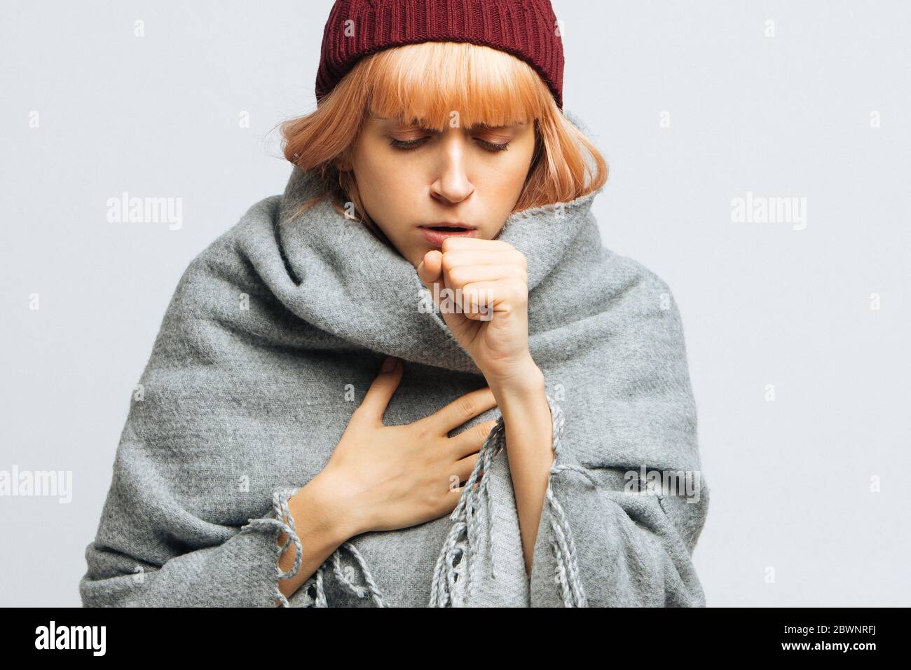 Cute sick young teen woman in red hat, wrapped in warm scarf coughing ...