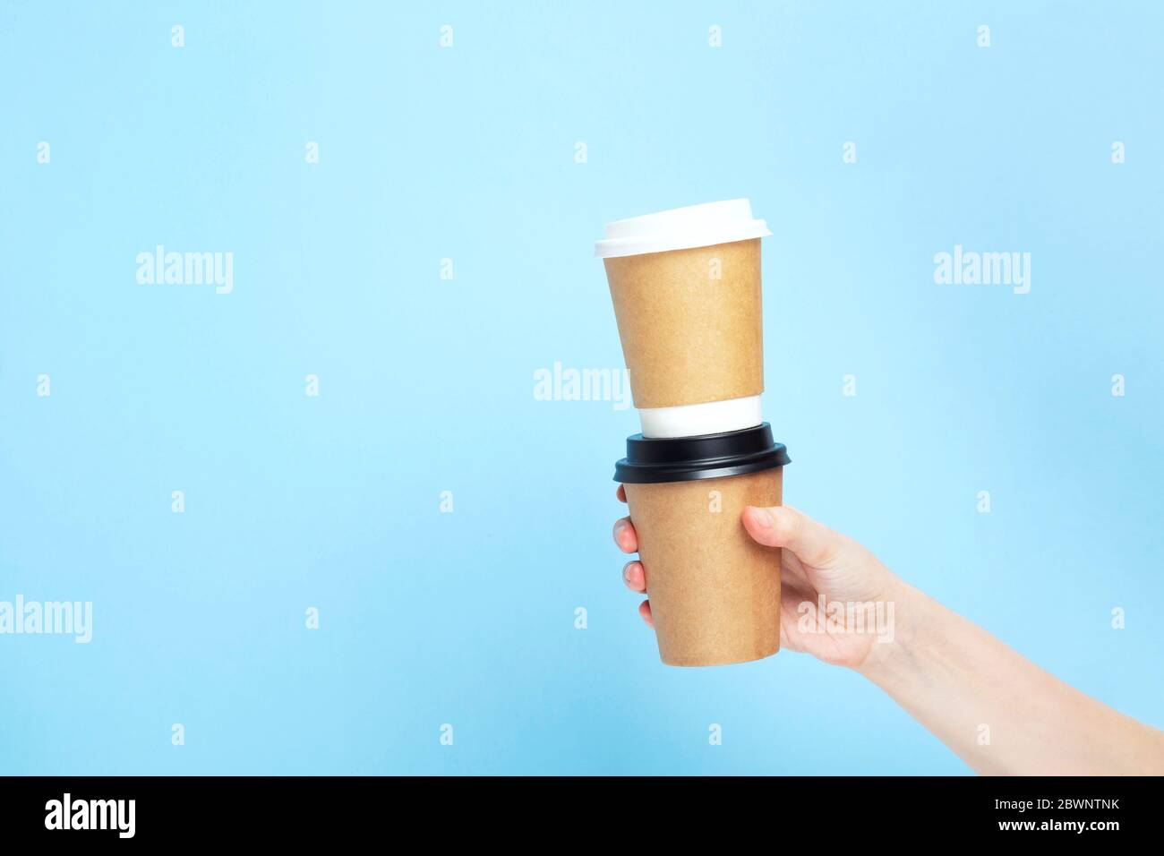 Woman holds hand holds two paper cups on blue background. Copy space ...