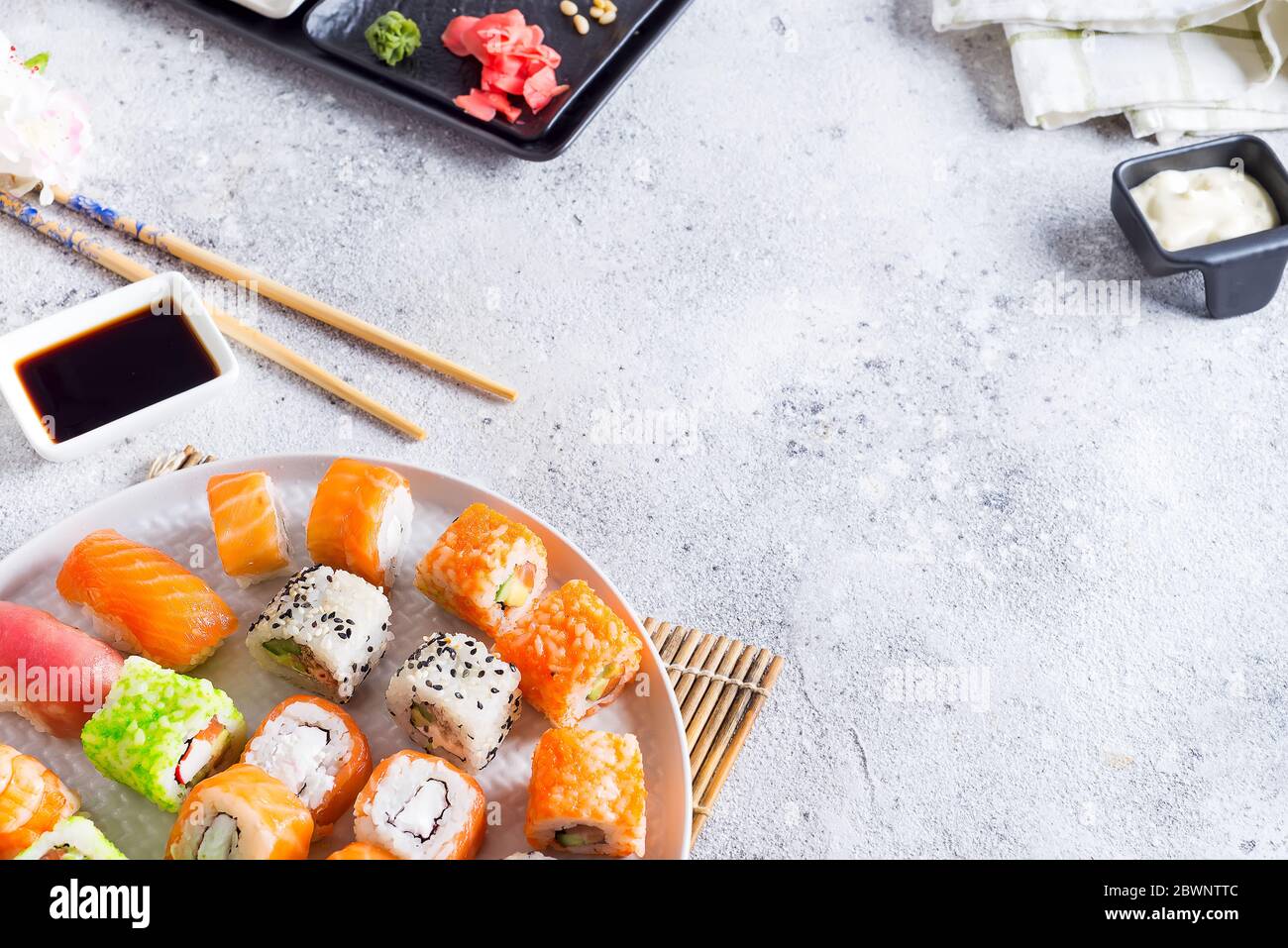 Various Fresh and delicious sushi set on white slate with wooden sticks ...