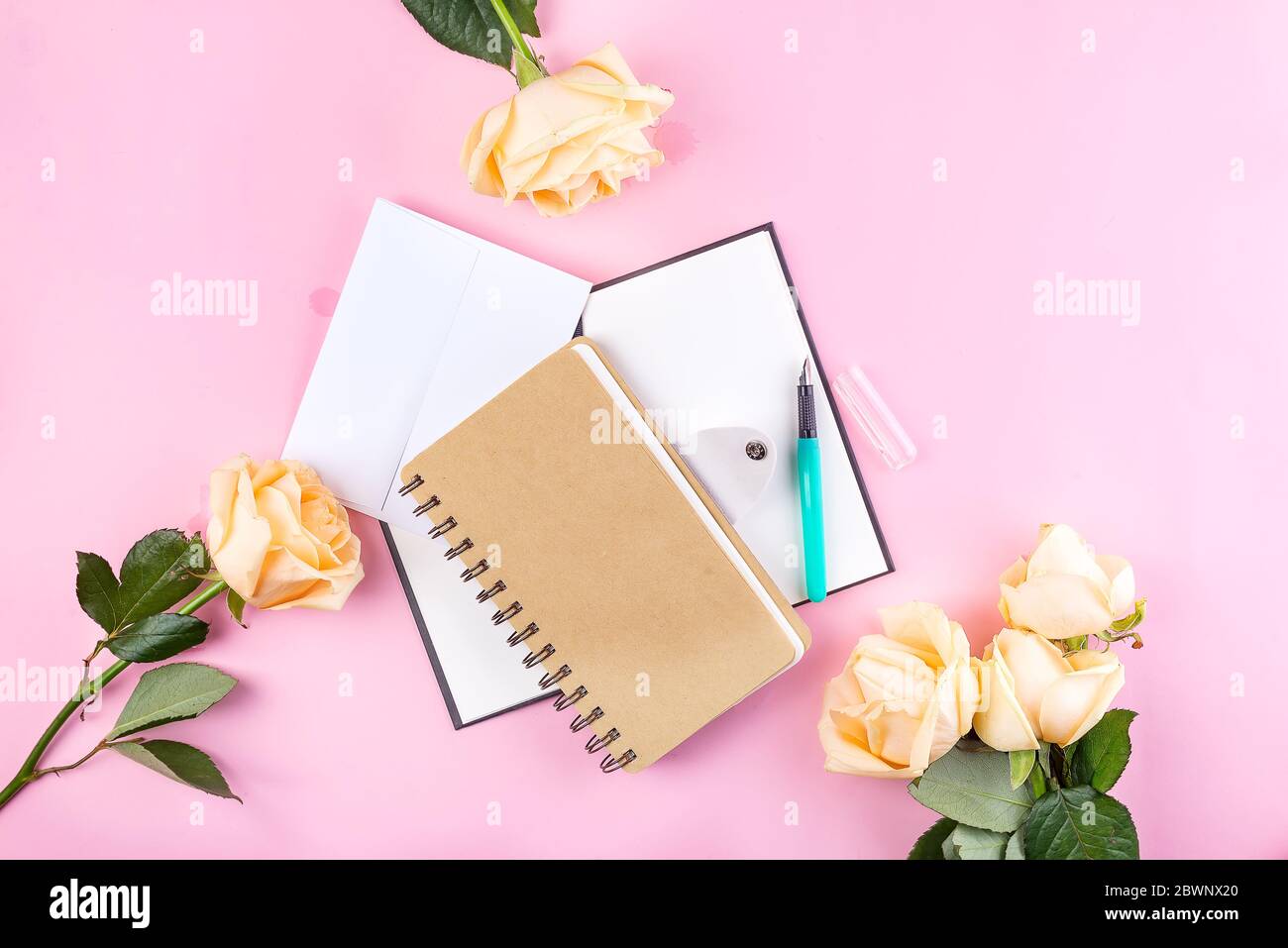 Top view of spiral kraft notebook and beige roses isolated on pink ...