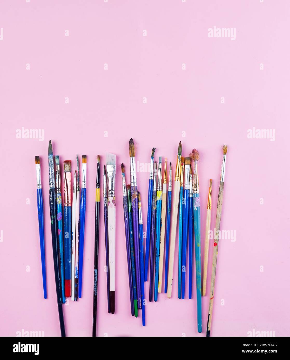 Paint brushes smeared in paint on a pink background. Flat lay Stock ...
