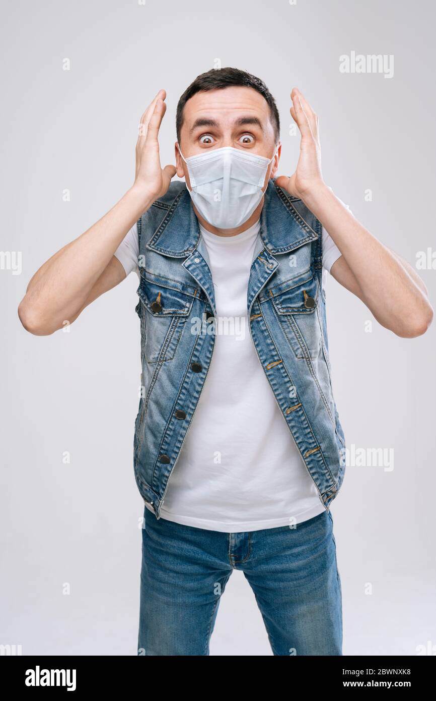 Scared man in medical mask afraid of something and looks into camera ...