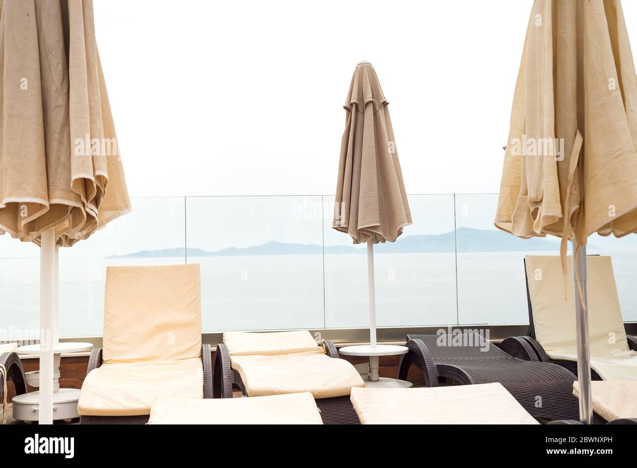 Sun umbrellas beige color and sun beds near swimming pool with with sea ...