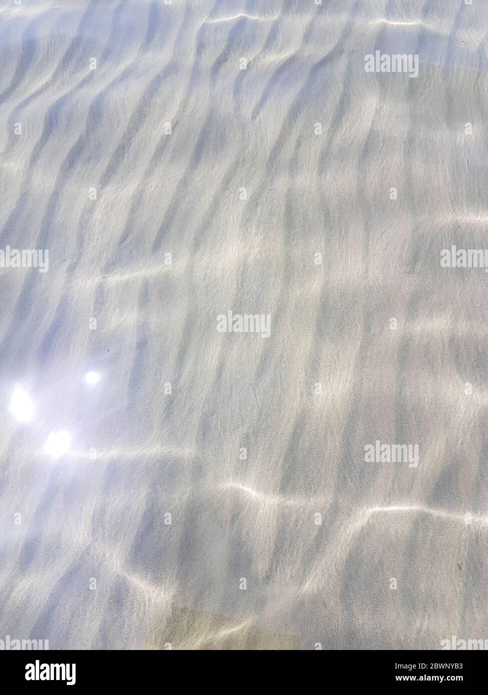 Natur water surface with sun reflection. Sea water background with sand ...