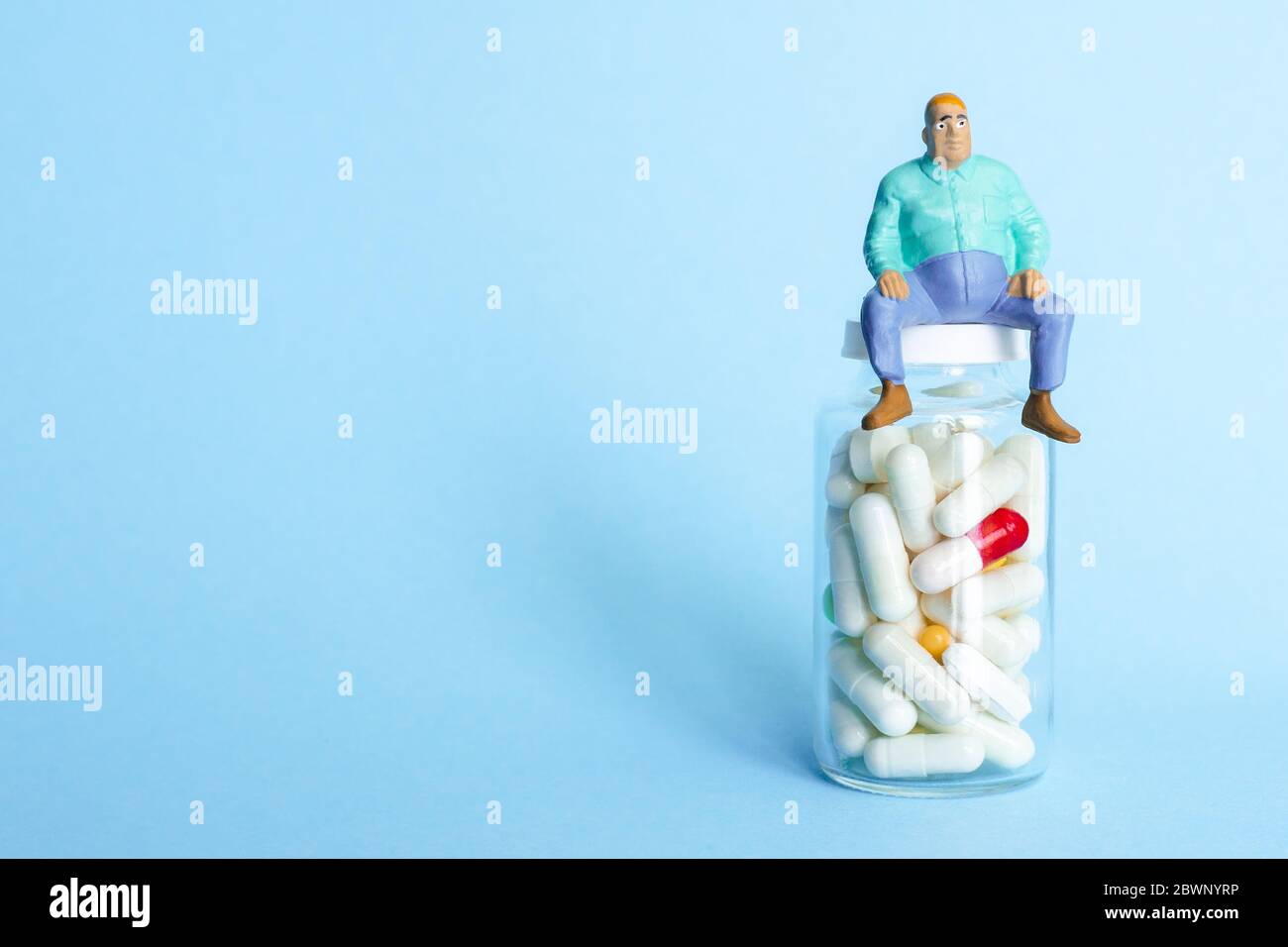 fat man on medicine bottle with obesity pills and capsules. healthcare ...