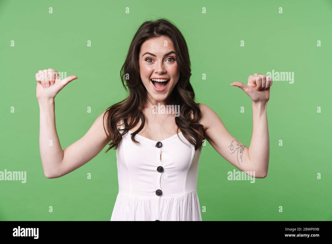 Image of excited caucasian woman smiling and pointing fingers at ...