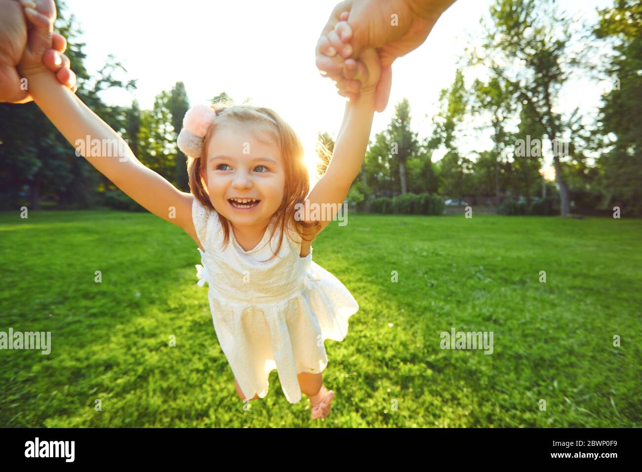 Happy child is twisted by hands in the park Stock Photo - Alamy