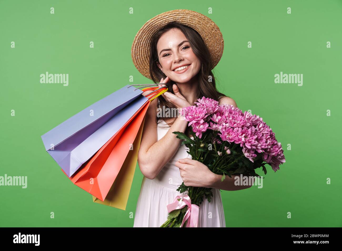 Image of smiling pretty woman in straw hat holding flowers and shopping ...