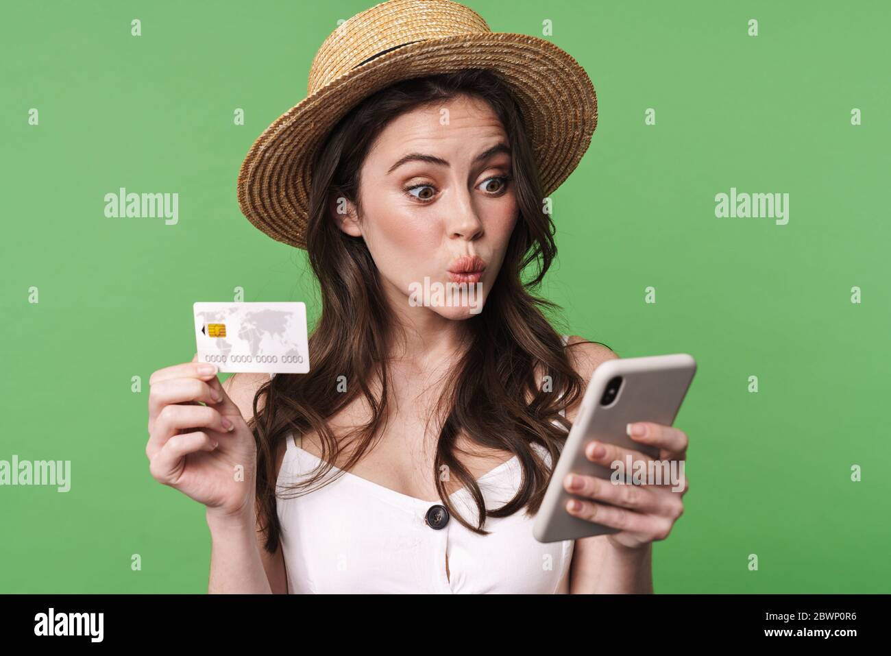 Image of amusing woman in straw hat holding credit card and using ...