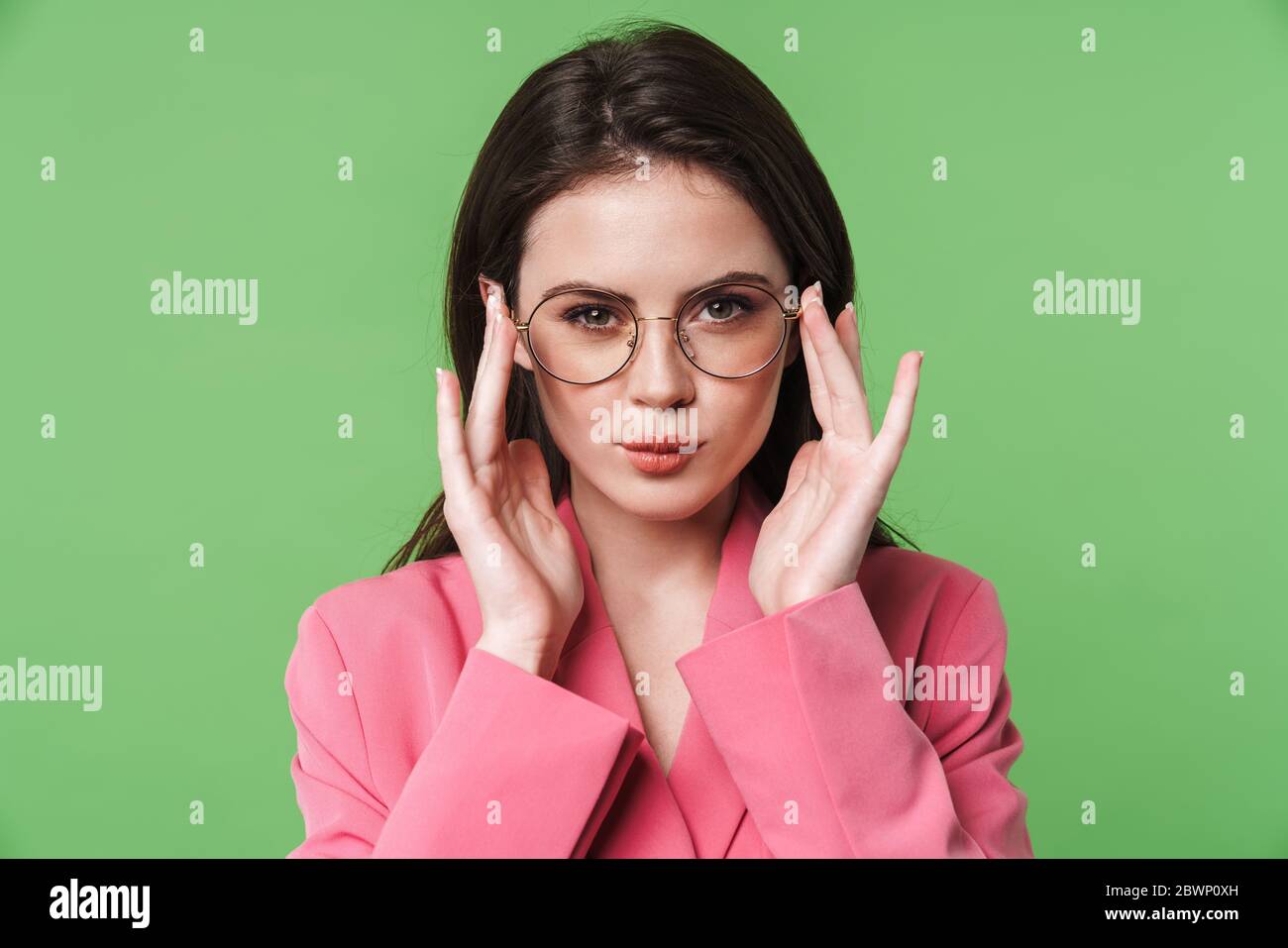 Image of thinking young woman in pink jacket holding eyeglasses ...