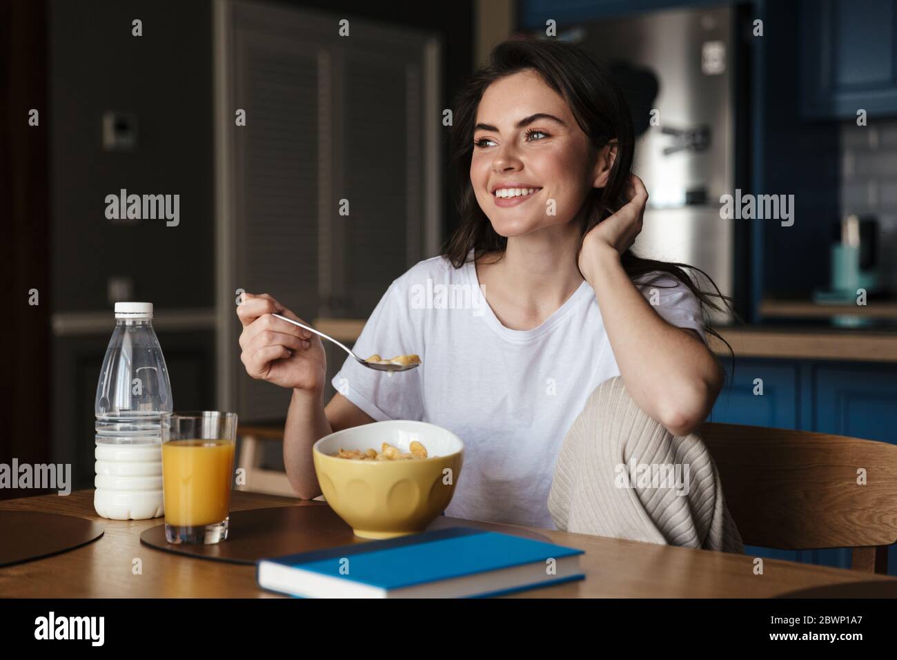 Attractive smiling young brunette woman having a healthy breakfast ...