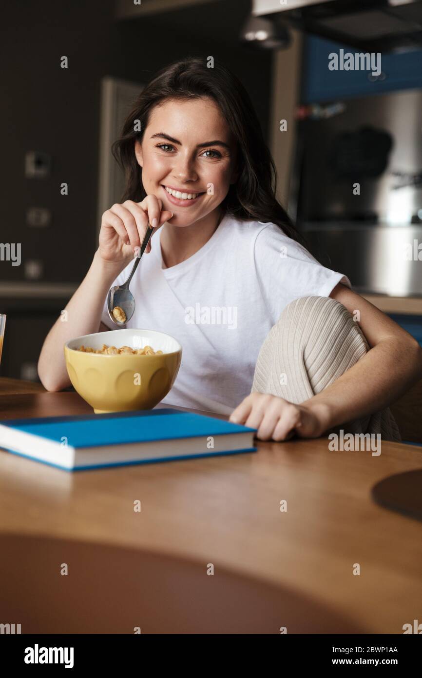 Attractive smiling young brunette woman having a healthy breakfast ...