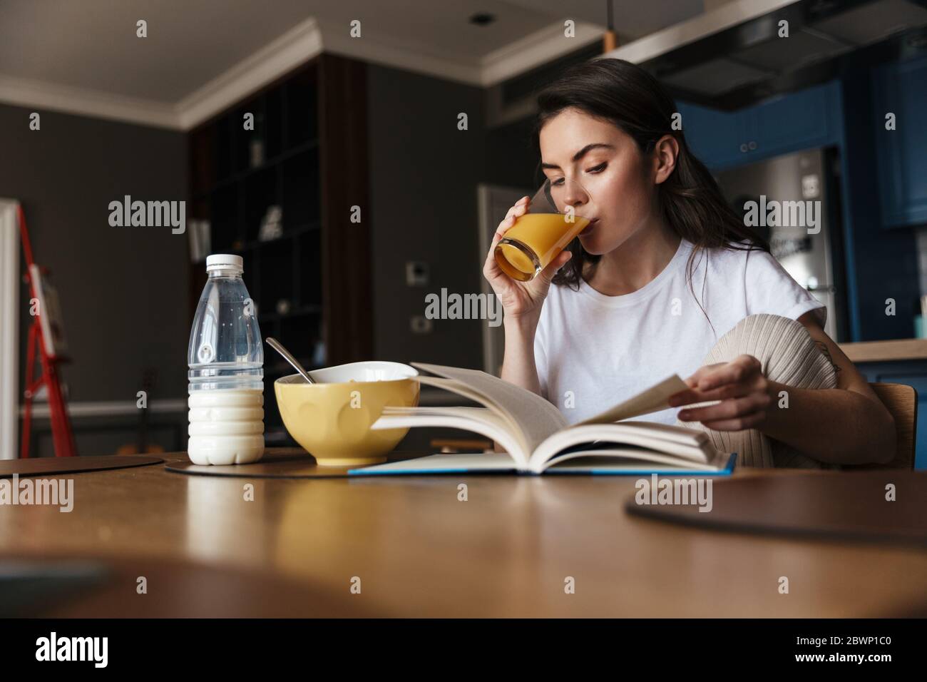 Attractive young brunette woman having a healthy breakfast reading a ...