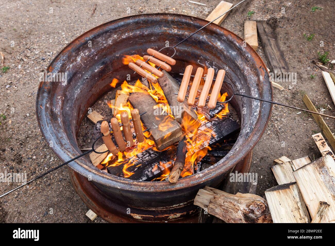 horizontal image of weiners being roasted on an open camp fire with ...