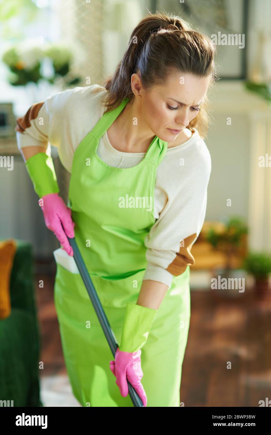 busy modern middle age woman in green apron and pink rubber gloves with ...