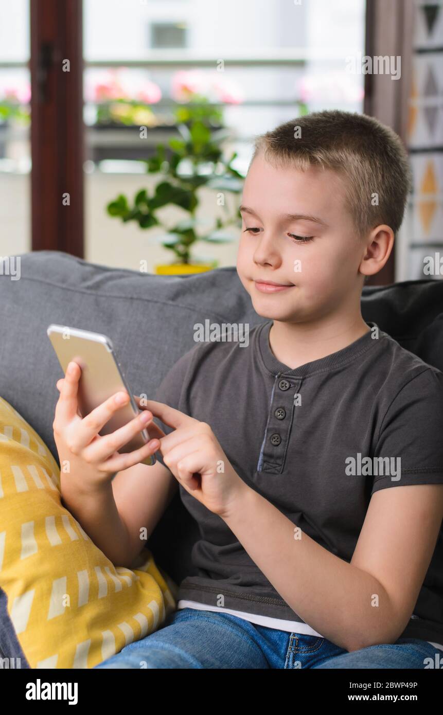 Young teen boy uses cell phone. A happy blonde boy talking by video ...