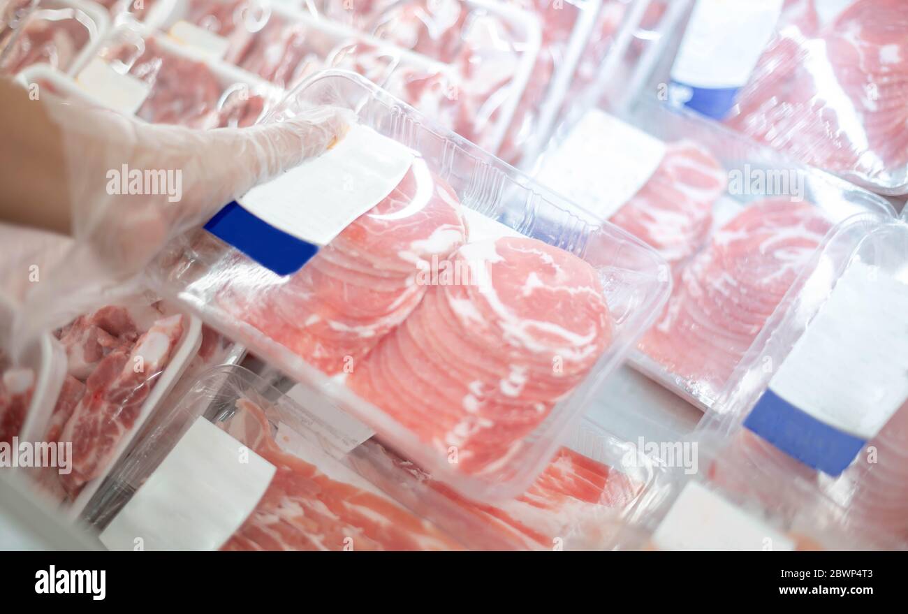 The supermarket employee preparing the Fresh pork meat slice on display ...