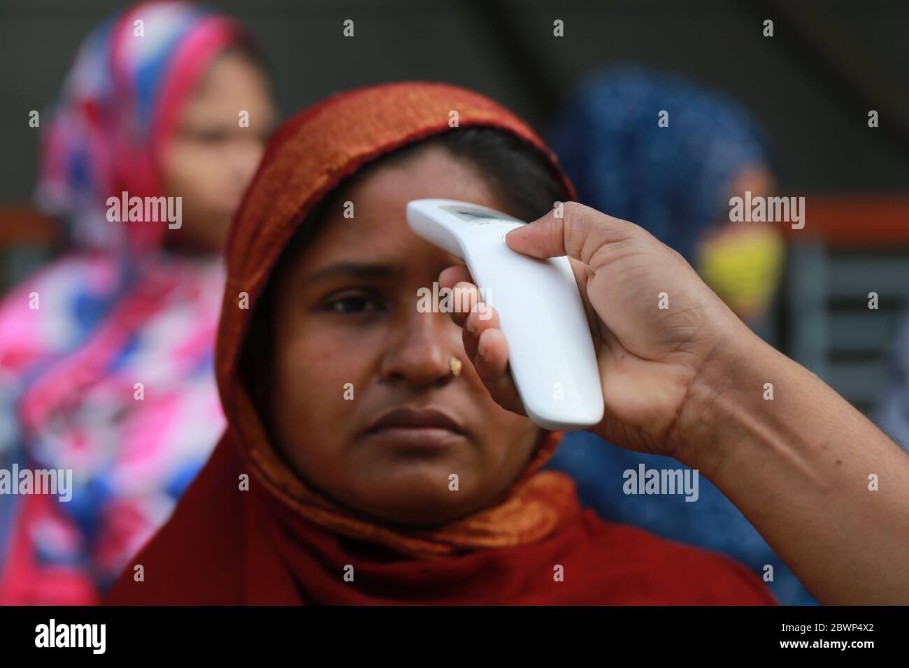 Female workers undergoing a body temperature scan as part of health ...