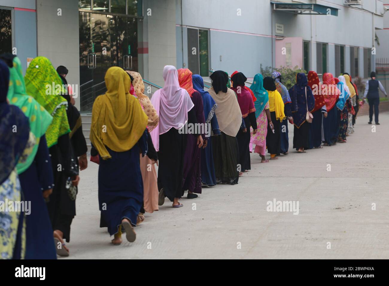 Female workers walk in a queue to join their works inside a garment ...
