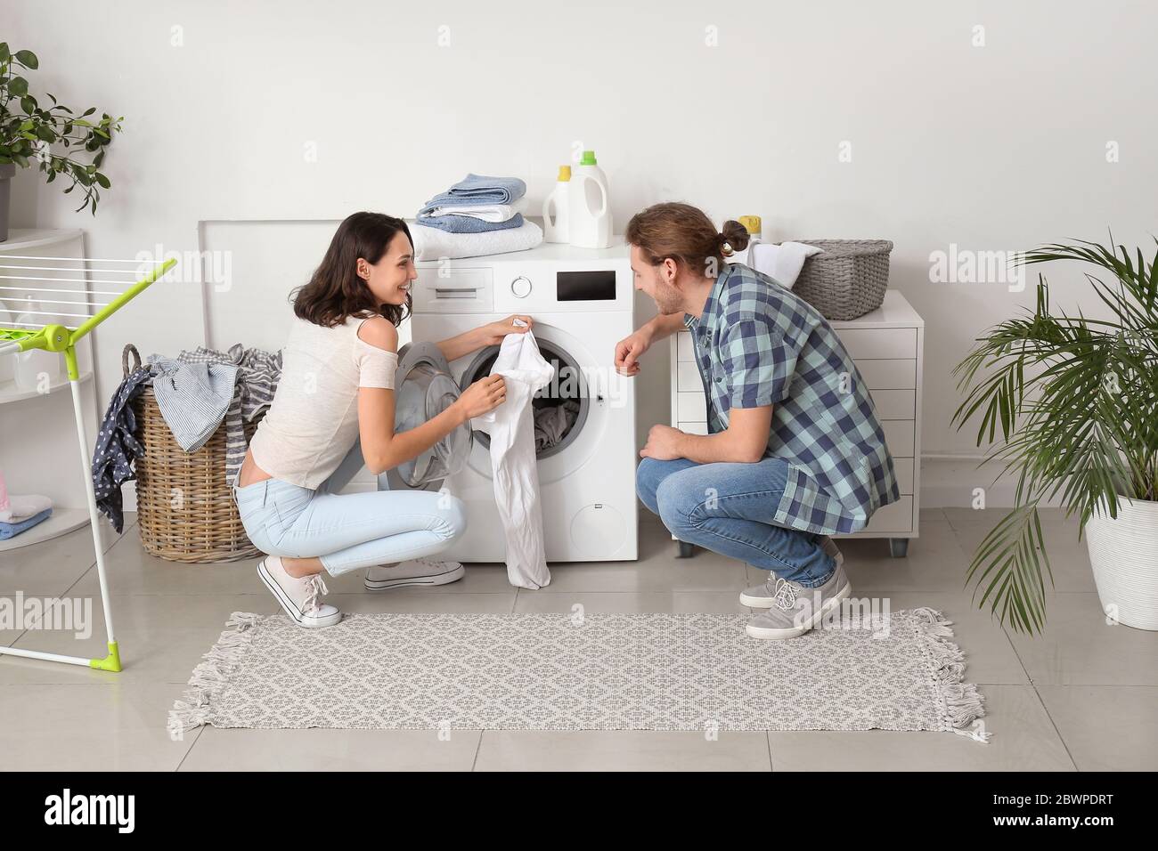 Happy young couple doing laundry at home Stock Photo - Alamy