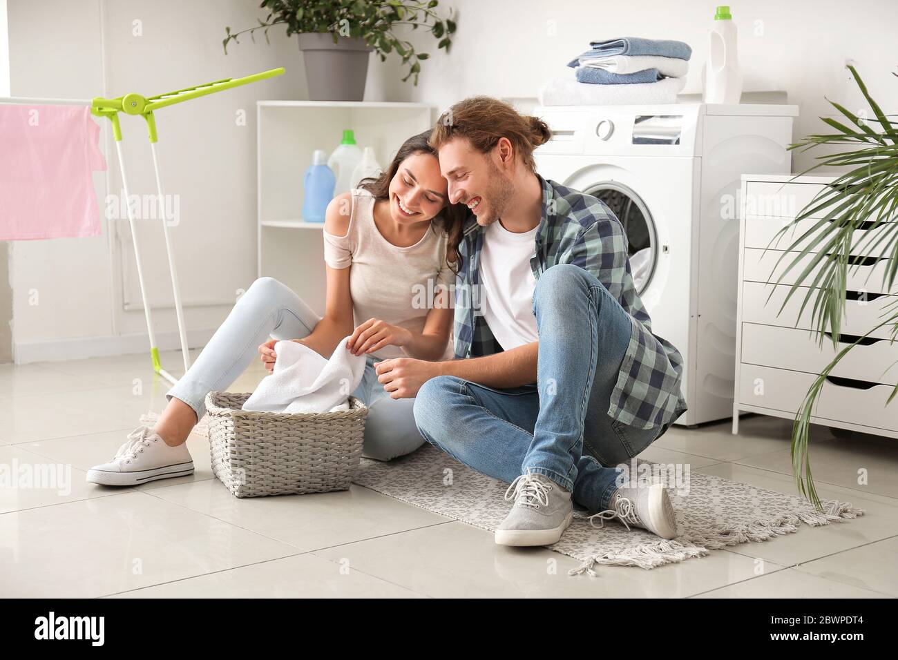Happy young couple doing laundry at home Stock Photo - Alamy