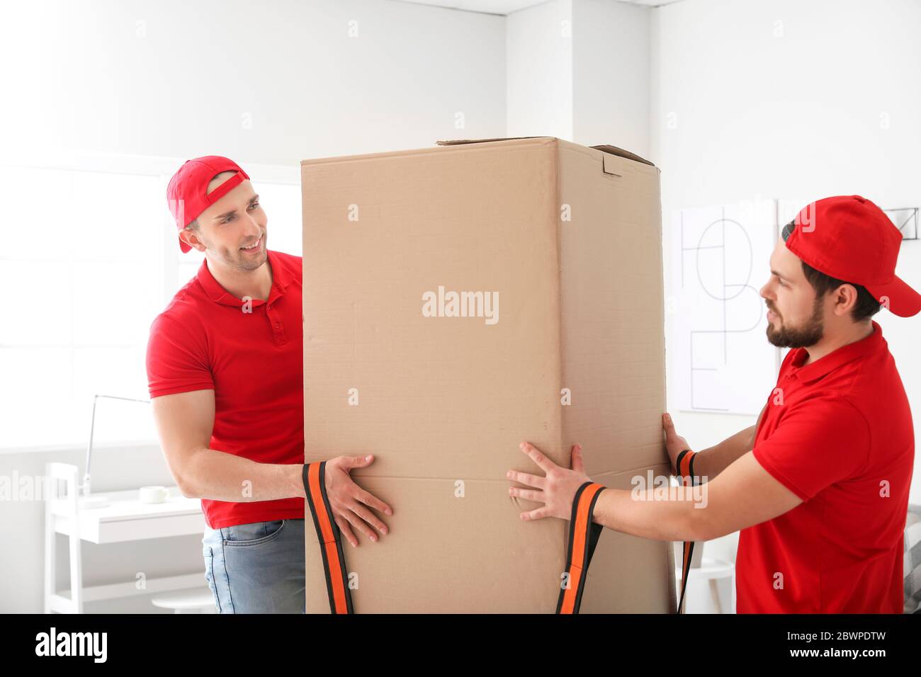 Loaders carrying big box by using cargo belts Stock Photo - Alamy