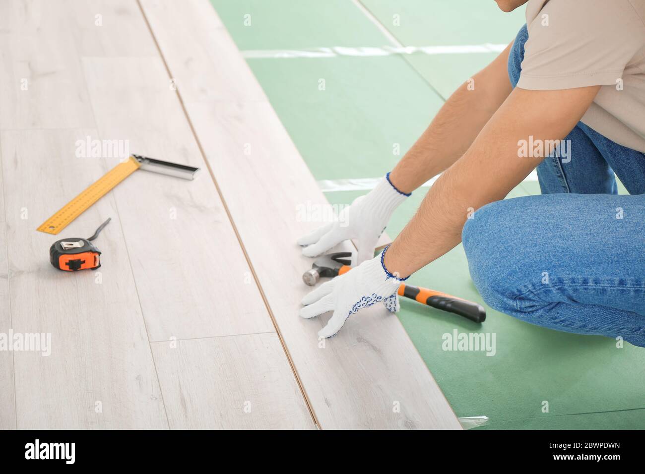 Carpenter installing laminate flooring in room Stock Photo - Alamy