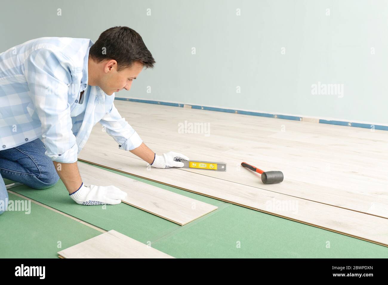 Carpenter installing laminate flooring in room Stock Photo - Alamy
