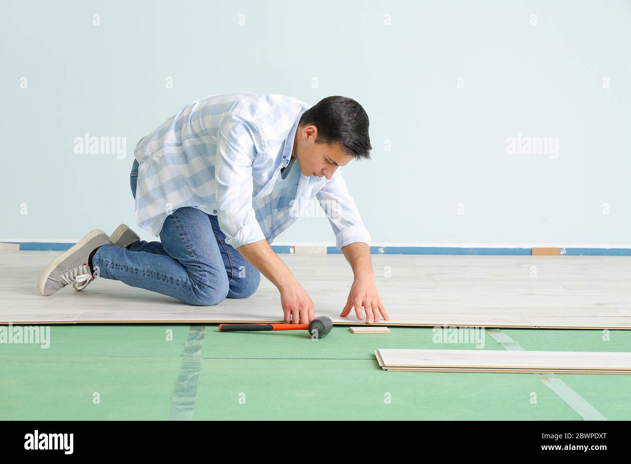 Carpenter installing laminate flooring in room Stock Photo - Alamy