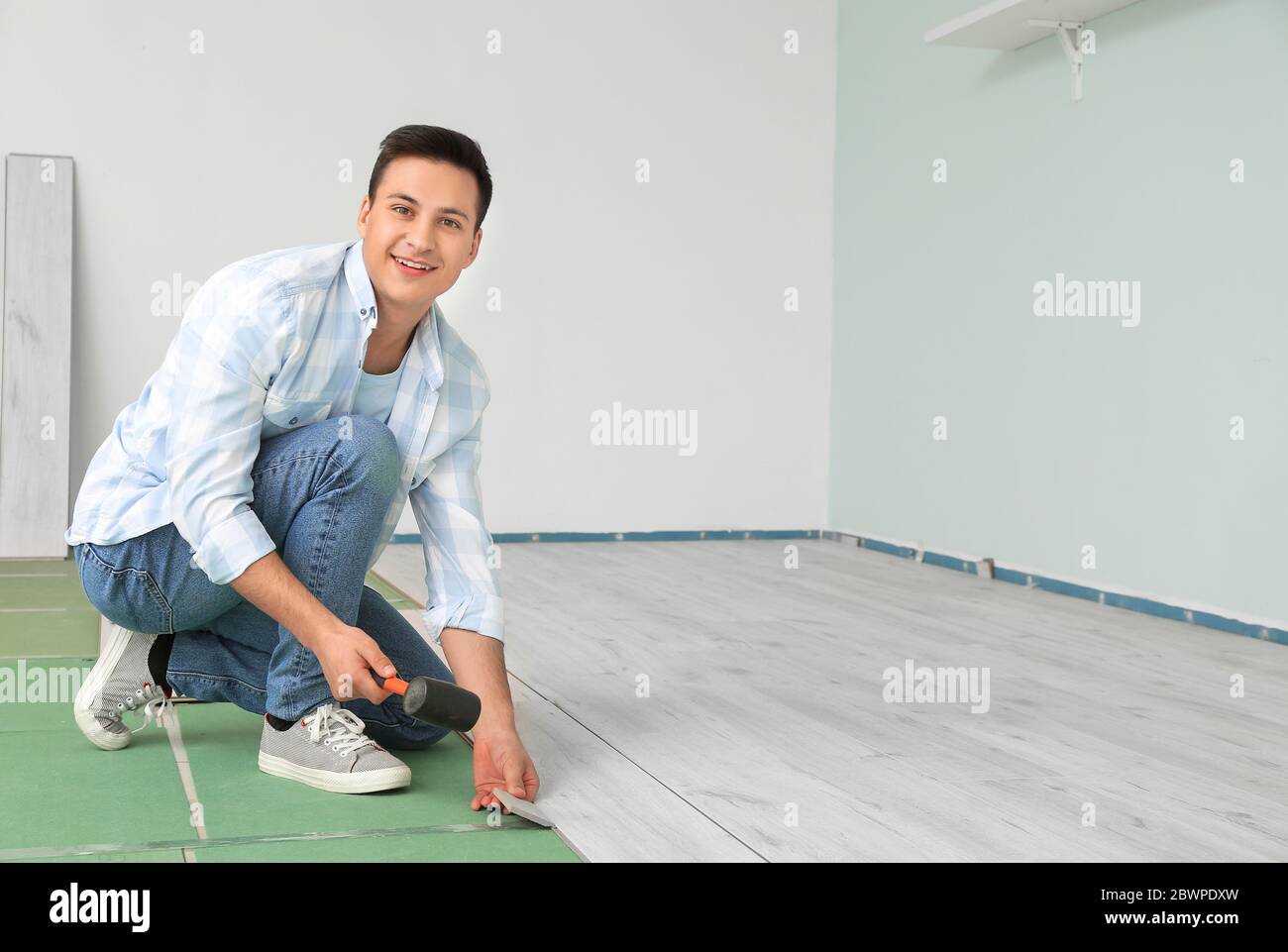 Carpenter installing laminate flooring in room Stock Photo - Alamy