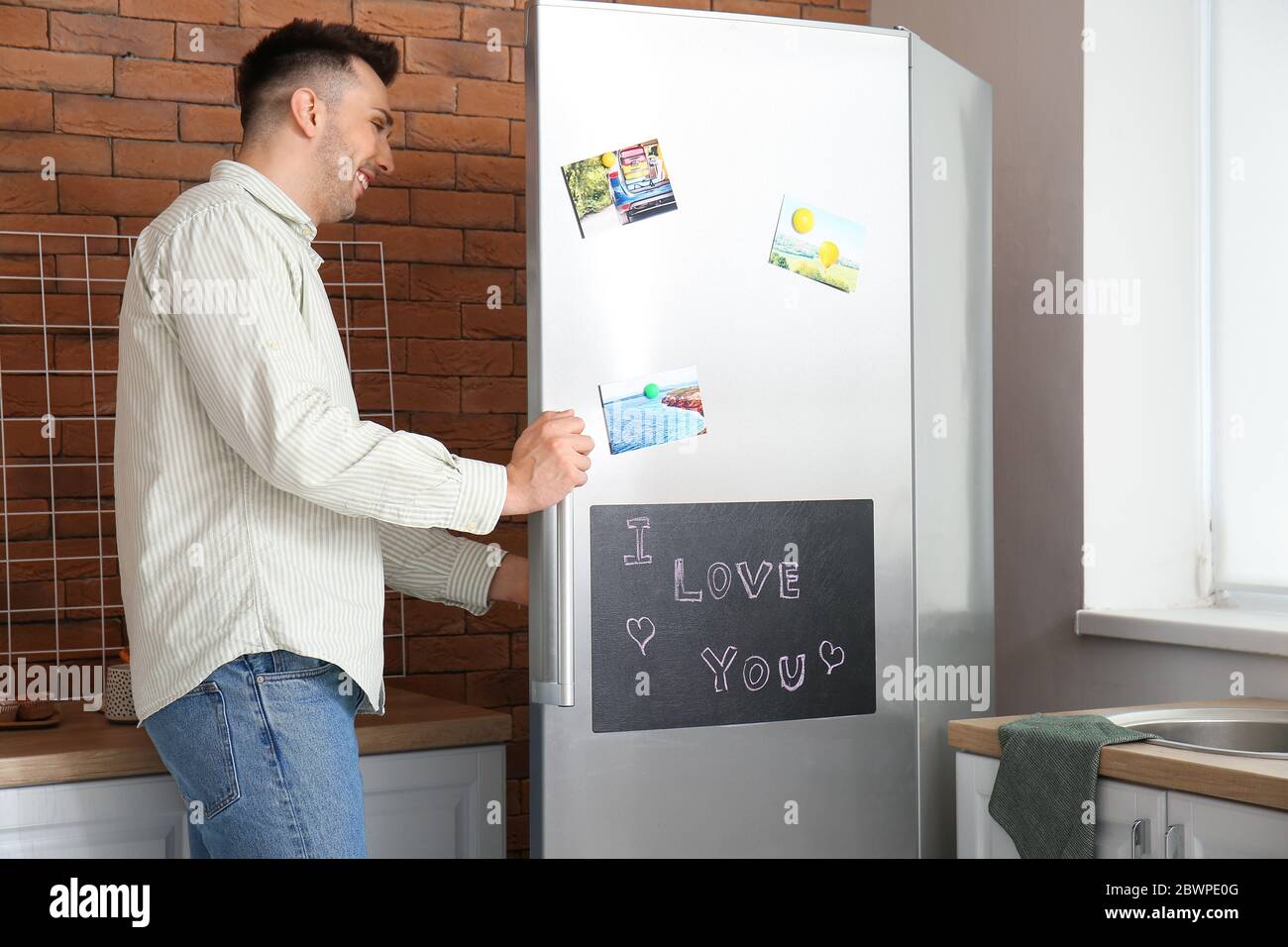 Young man opening refrigerator in kitchen Stock Photo - Alamy
