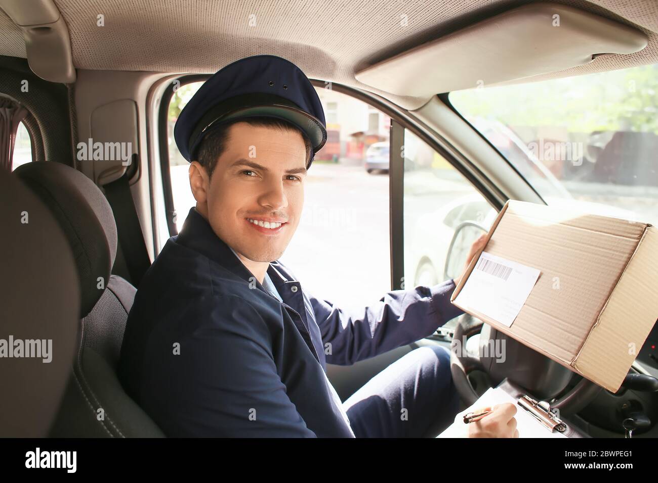 Handsome young postman in car Stock Photo - Alamy