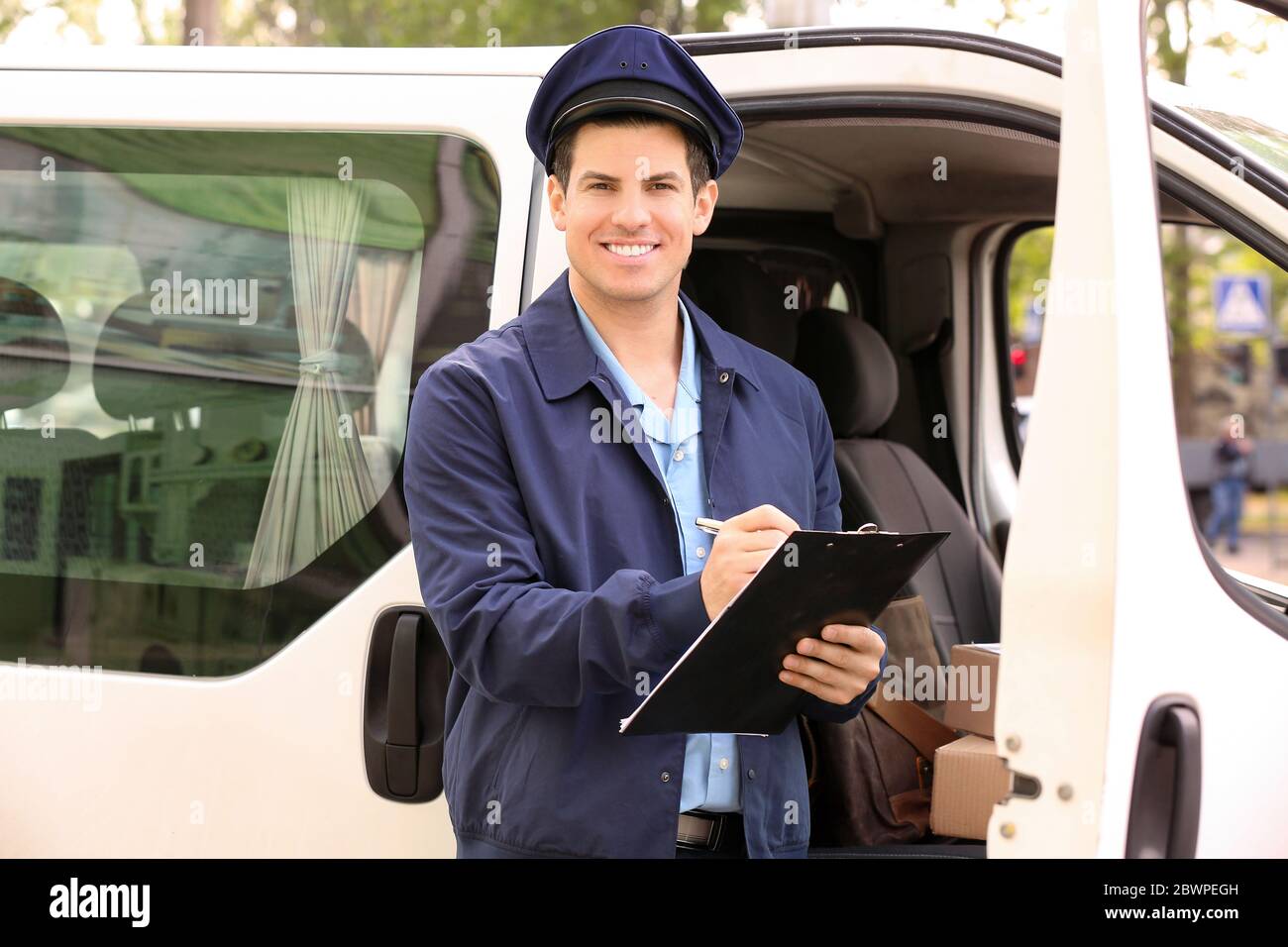 Handsome young postman near car outdoors Stock Photo - Alamy