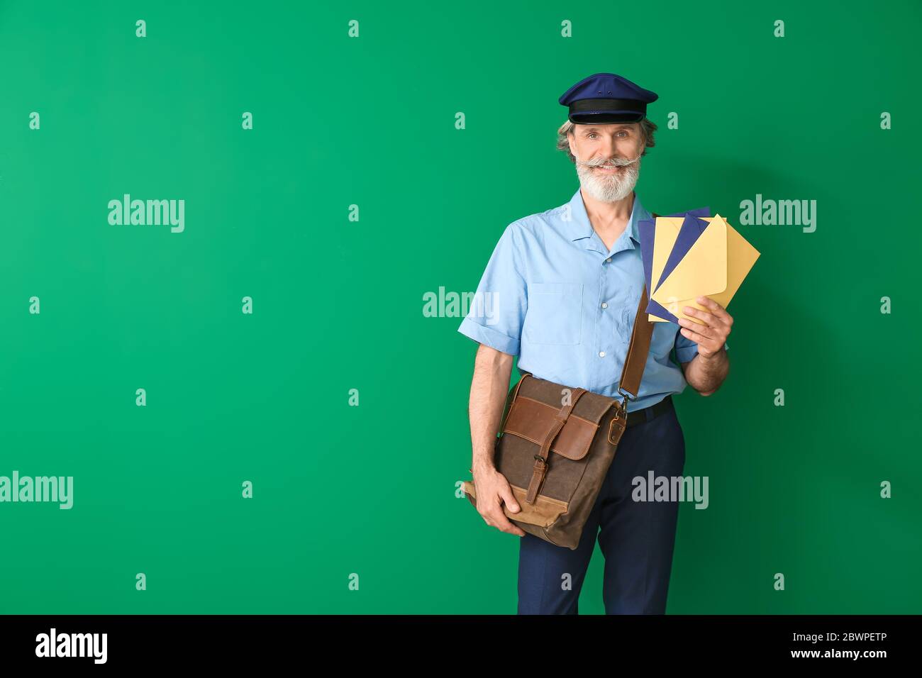 Handsome old postman on color background Stock Photo - Alamy