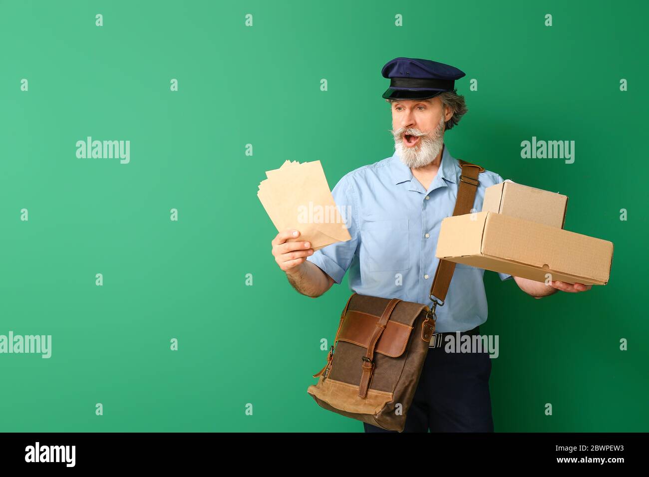 Surprised old postman on color background Stock Photo - Alamy