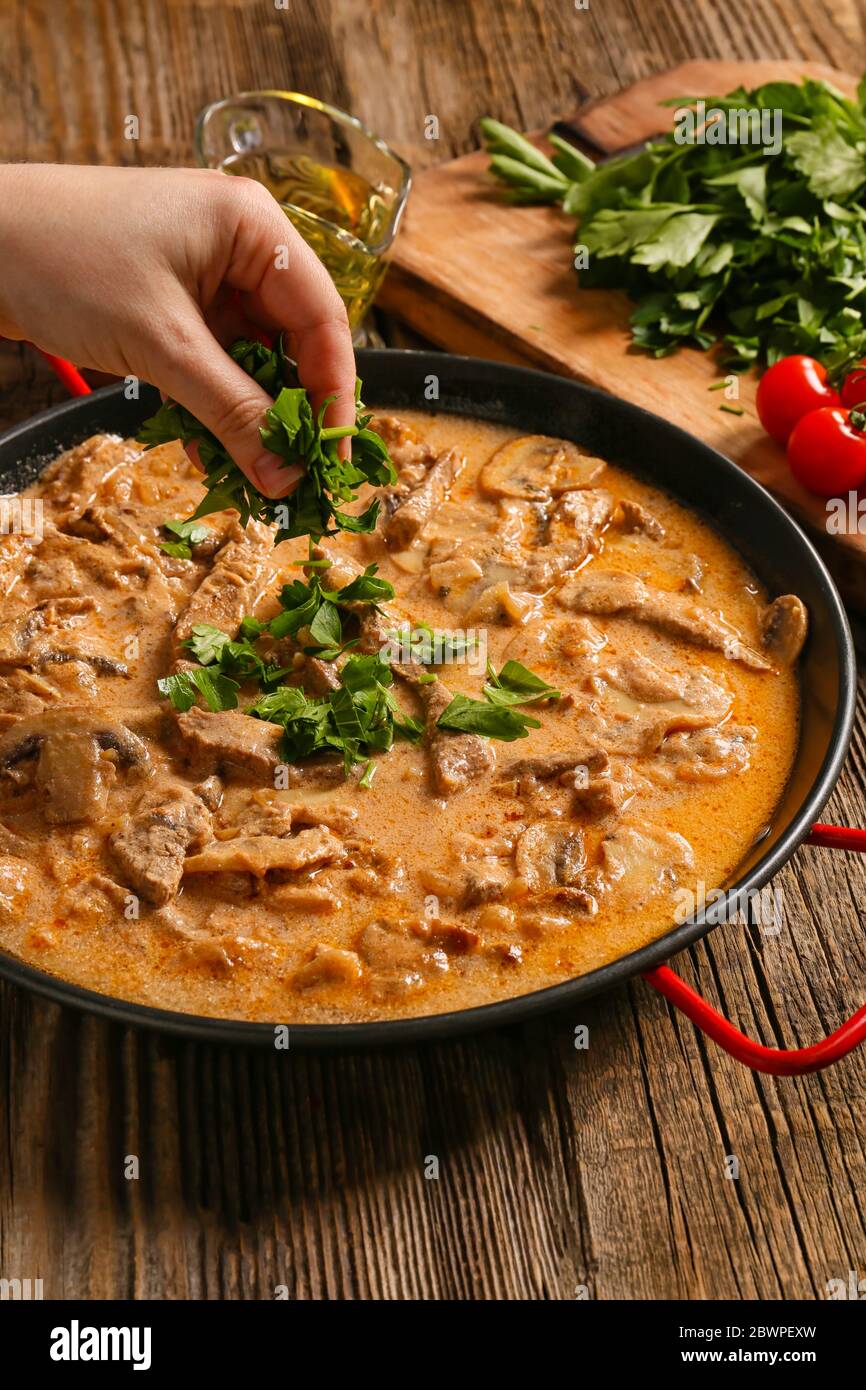 Woman cooking tasty beef stroganoff on table Stock Photo - Alamy
