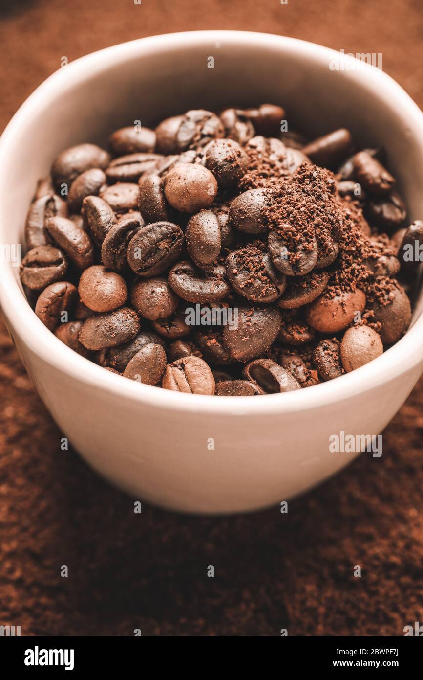Cup with roasted coffee beans on powder, closeup Stock Photo - Alamy