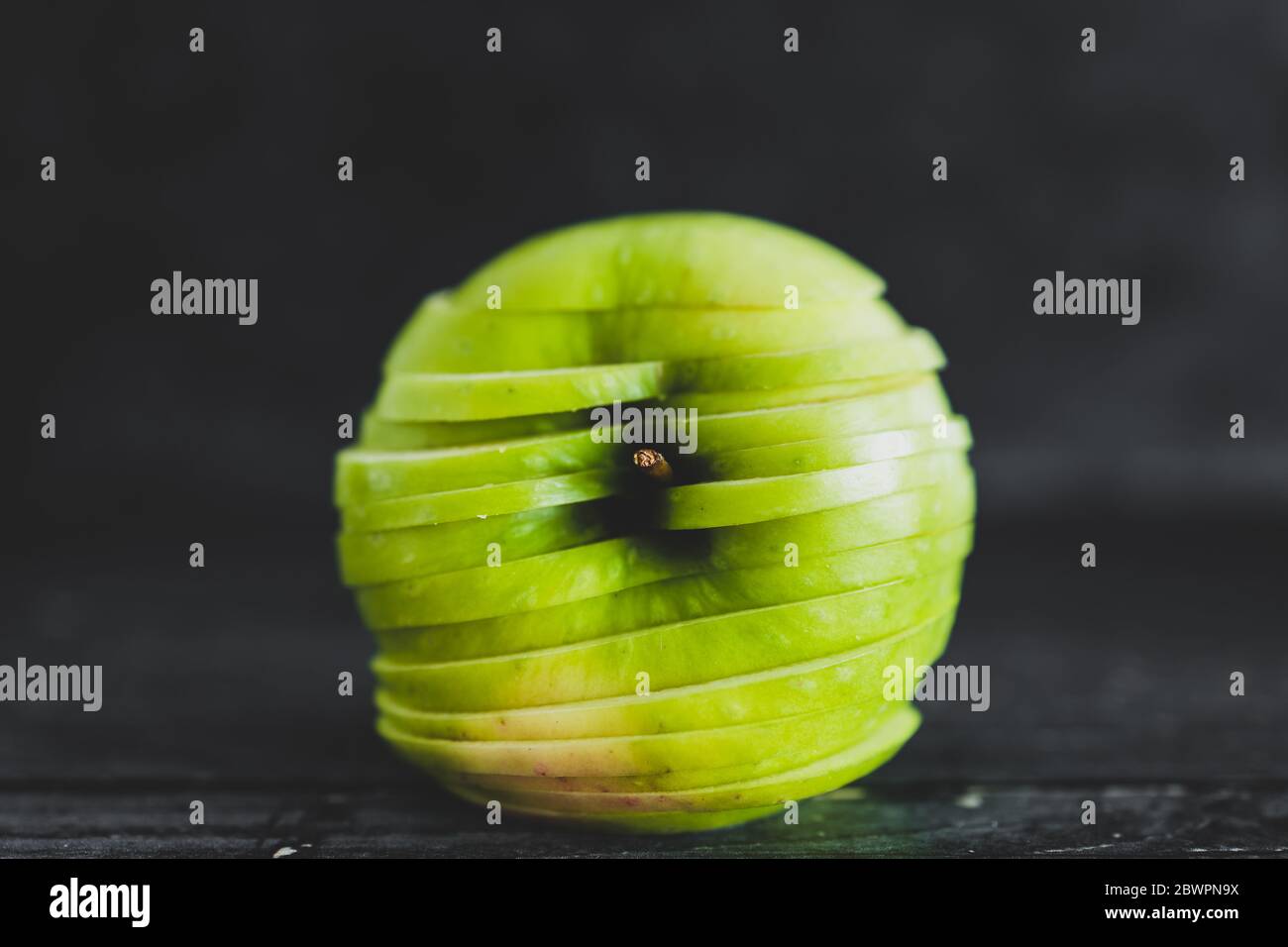 healthy plant-based food ingredients concept, green apple cut into thin ...