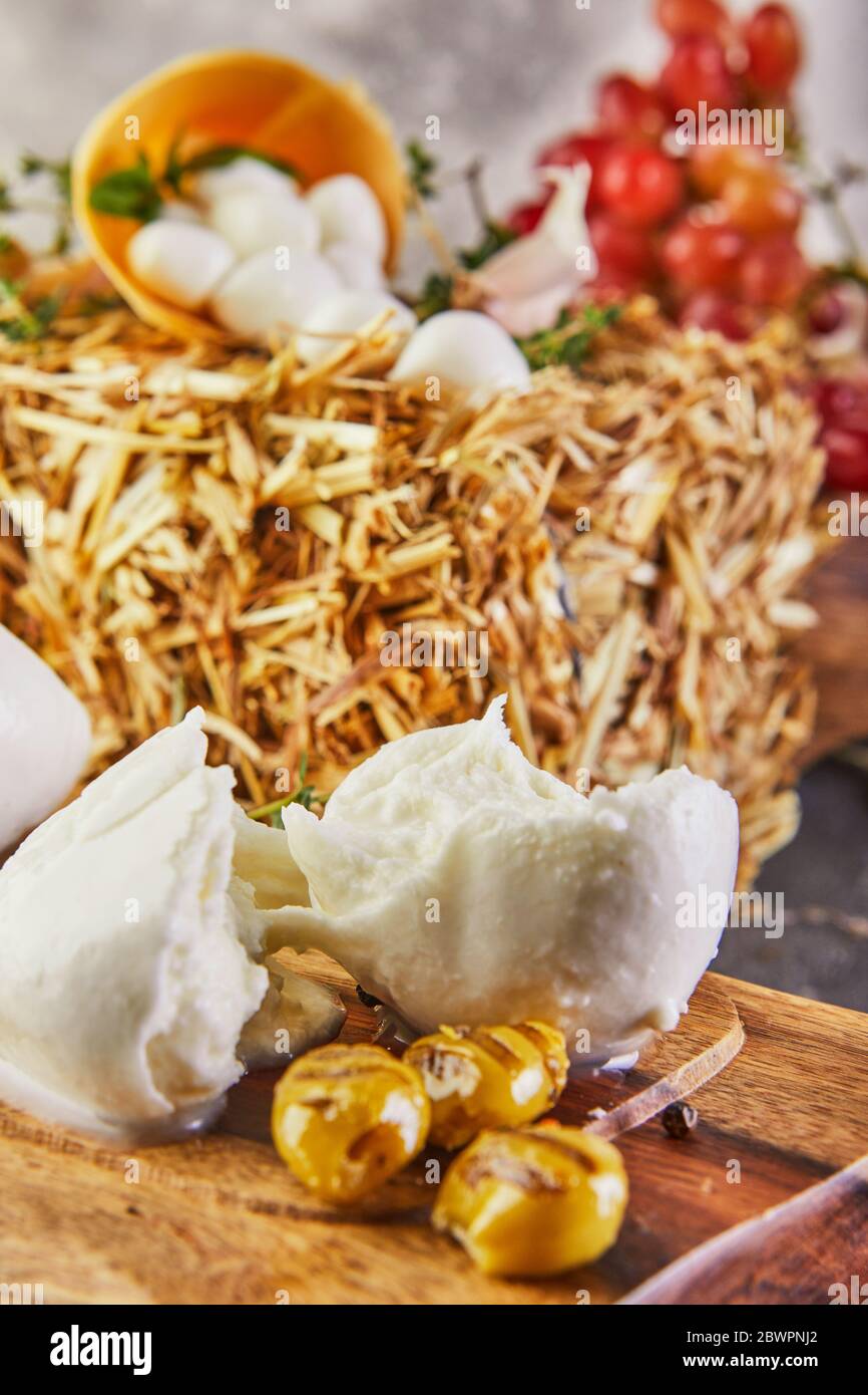Fresca mozzarella with garlic and smoked olives on a wooden stand on a ...