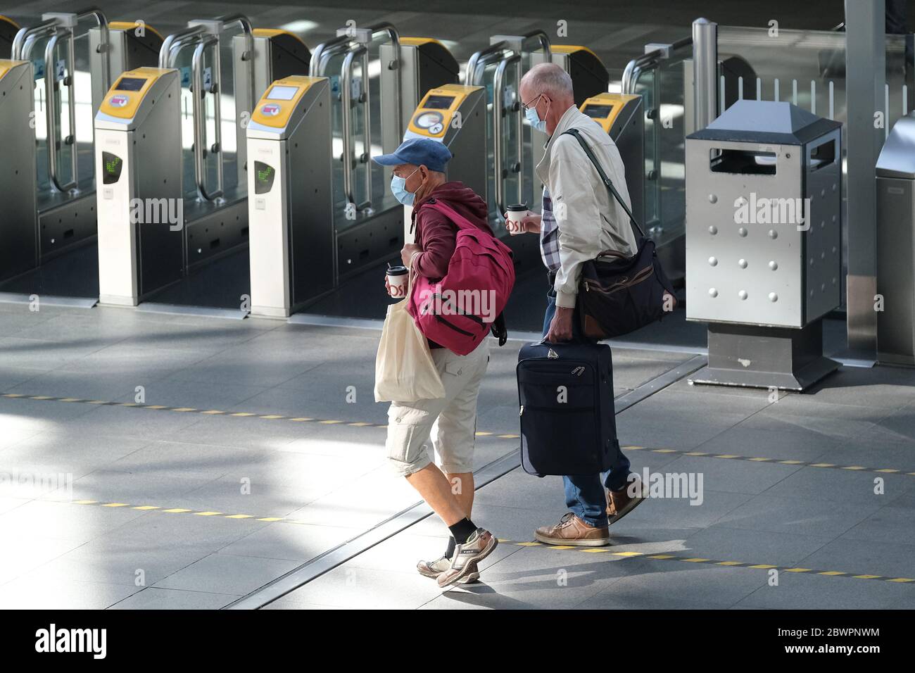 Elderly men wearing face masks walk through The Hague central station ...