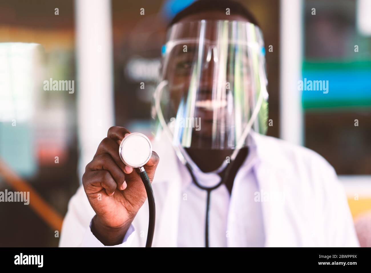 African doctor wear face shield and holding stethoscope with kind and ...