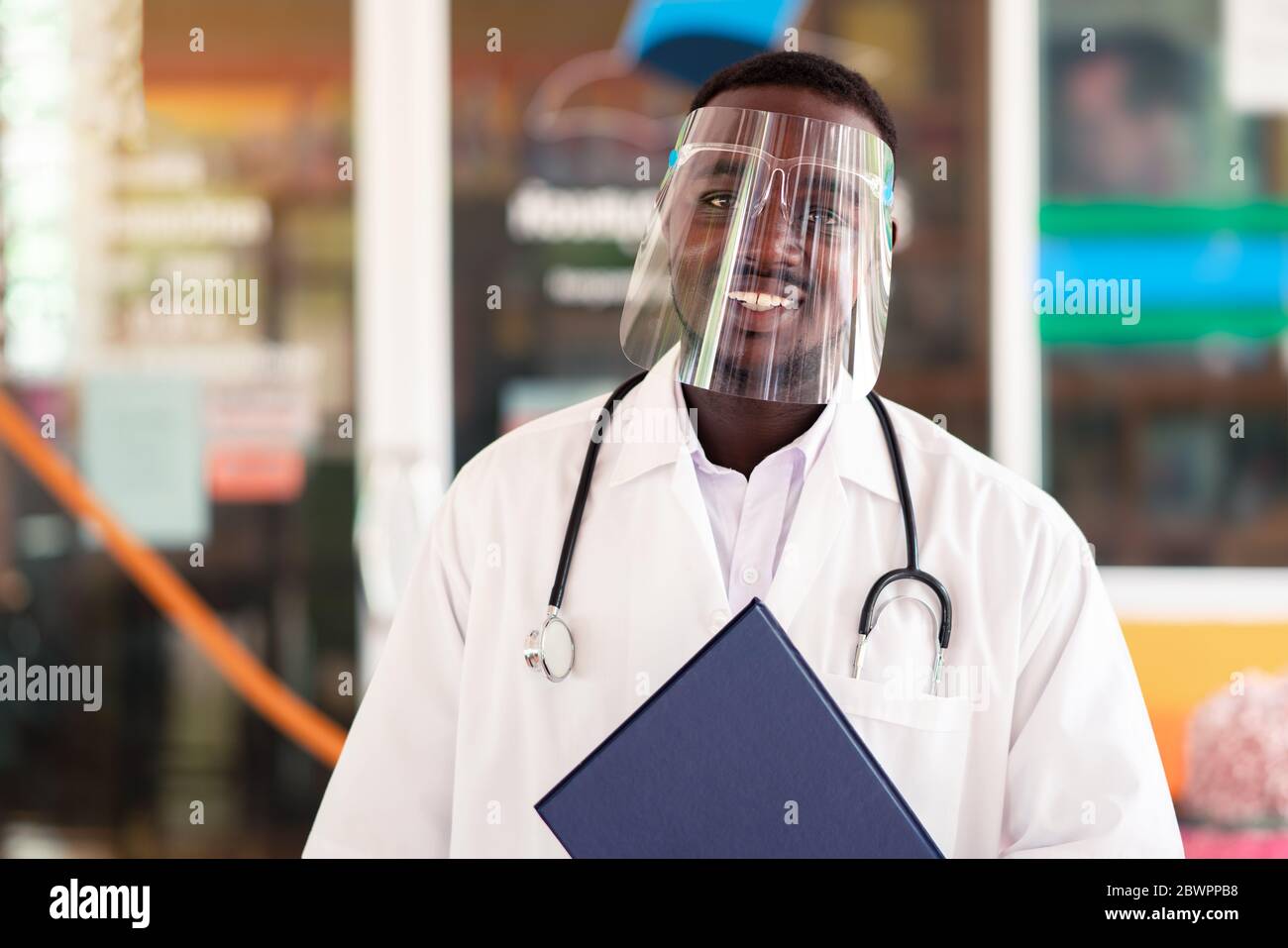 African doctor wear face shield and holding stethoscope with kind and ...