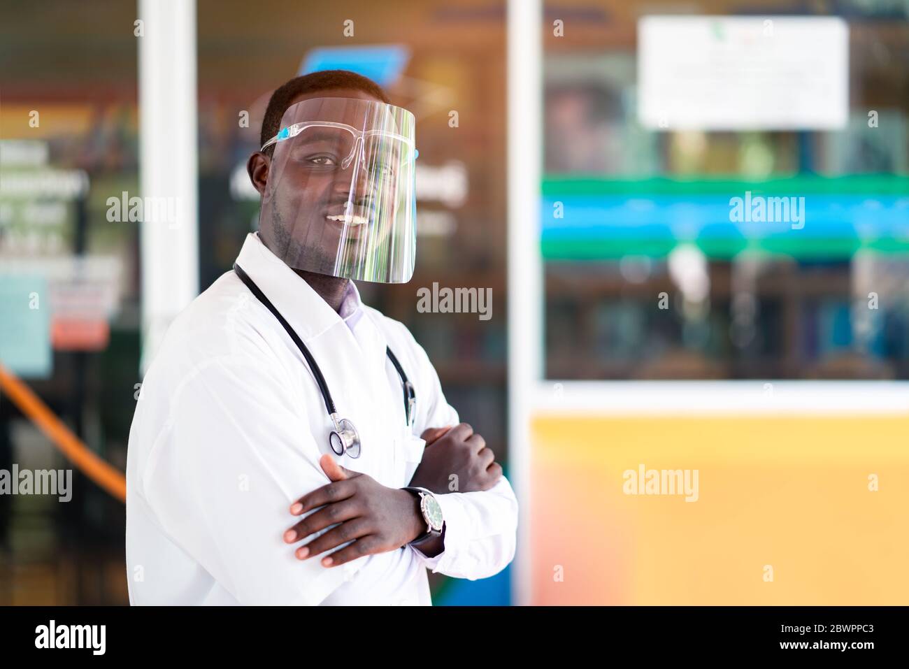 African doctor wear face shield and holding stethoscope with kind and ...