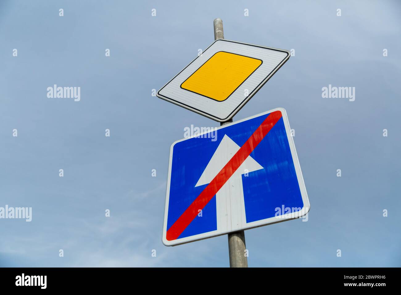 Road sign main road and one-way road end sign on blue sky background ...