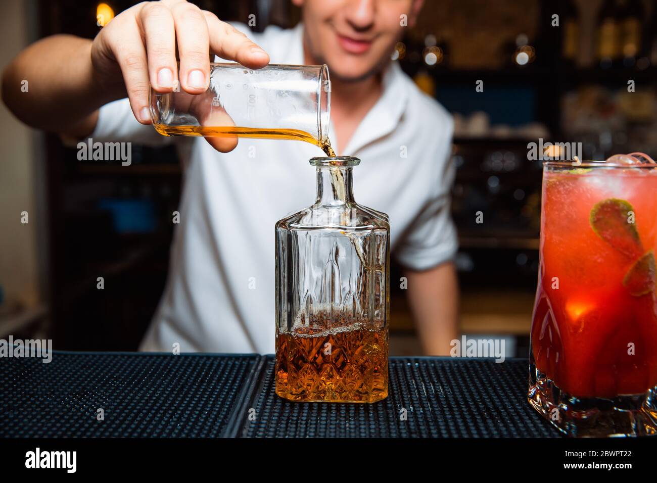 The barman pours whiskey into a transparent decanter Stock Photo - Alamy