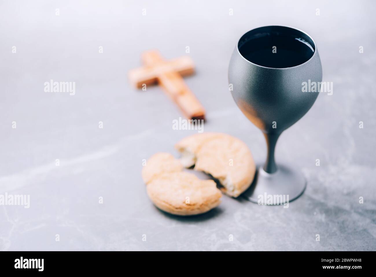 Unleavened bread, chalice of wine, wooden cross on grey background ...