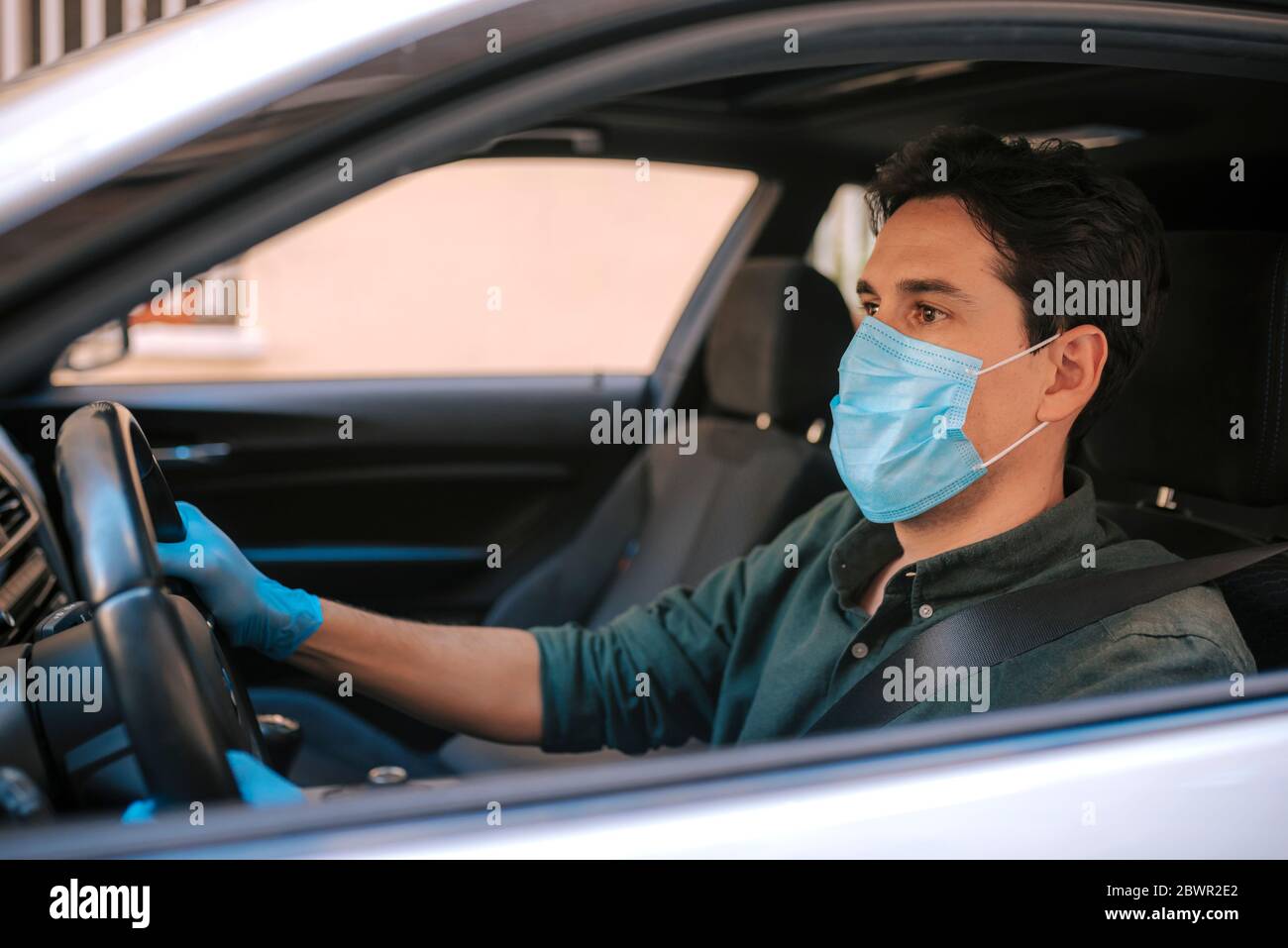 a man driving a car puts on a medical mask during an epidemic, a taxi ...