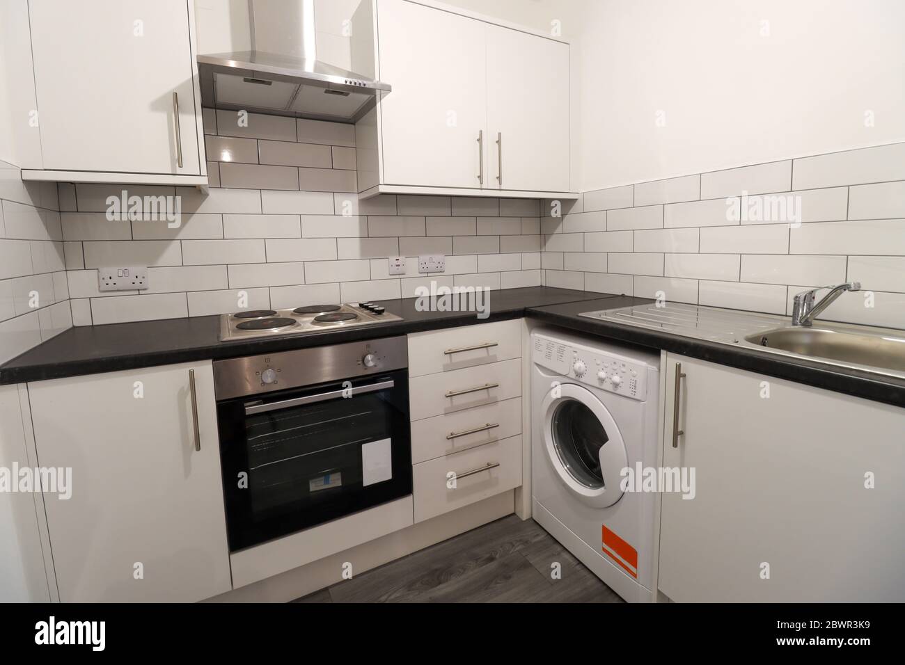 A modern British apartment kitchen with a grey wooden floor with white ...