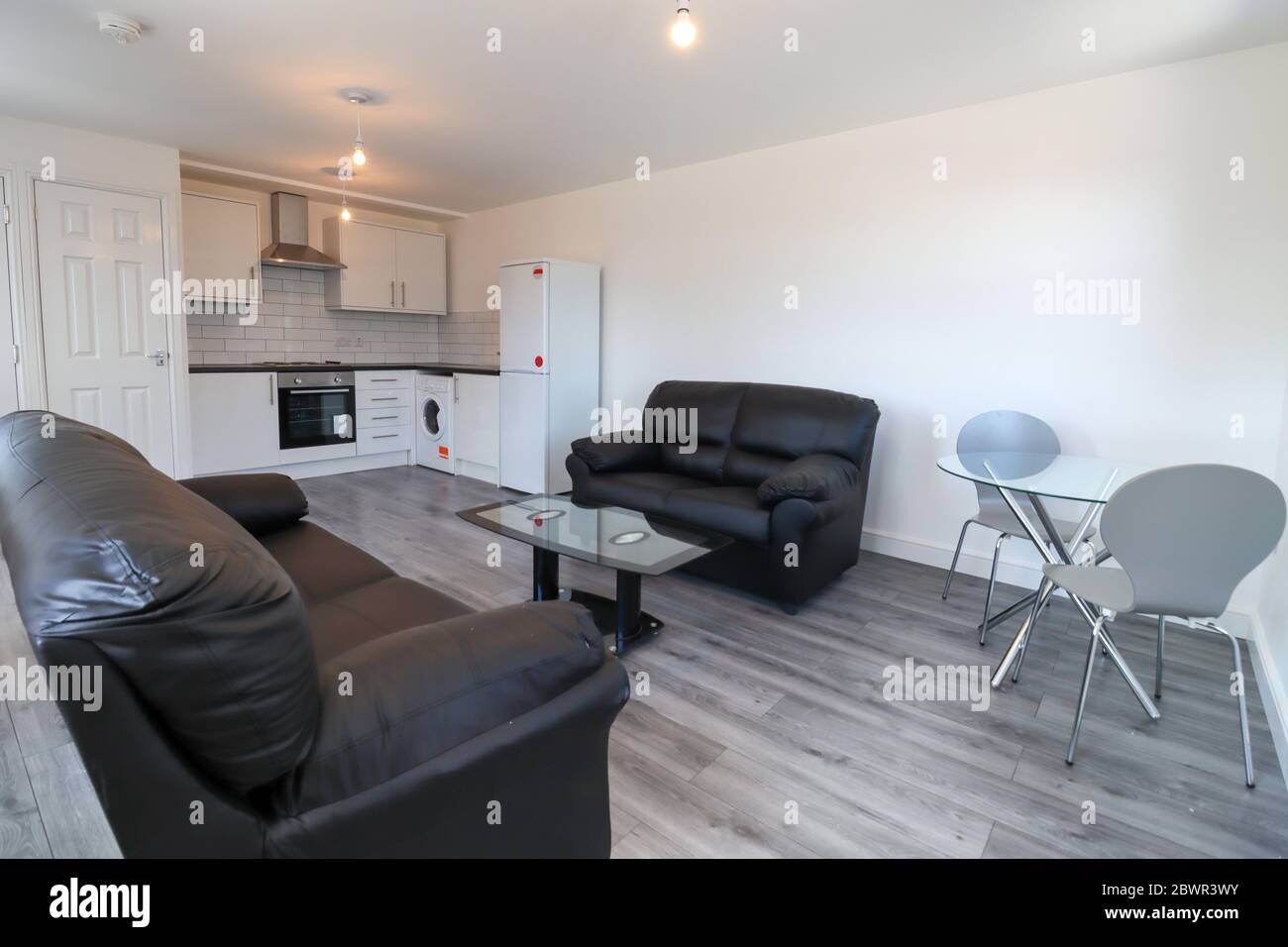 A modern British apartment living room and kitchen with black leather ...