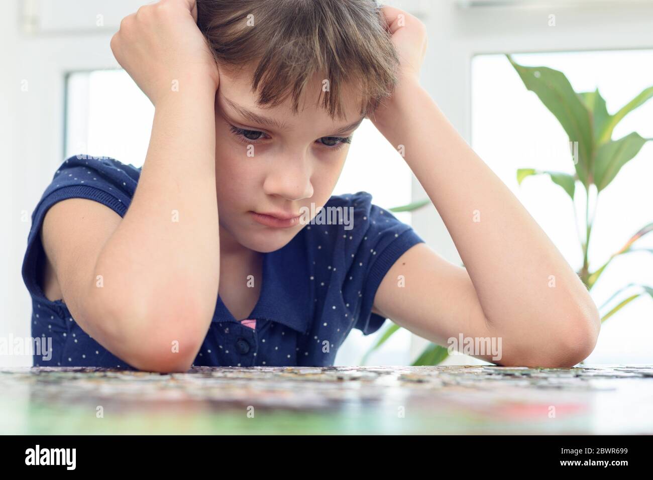Girl thinking over a puzzle while sitting at home at the table Stock ...